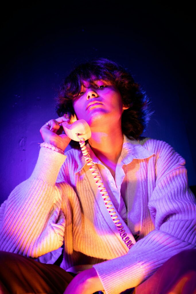 Moody portrait of a person using a vintage phone in vibrant neon light.