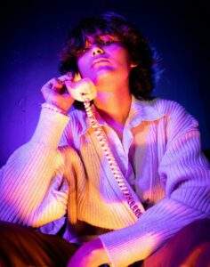 Moody portrait of a person using a vintage phone in vibrant neon light.